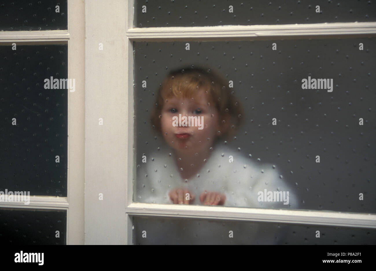 little girl pressing face against textured glass window Stock Photo - Alamy