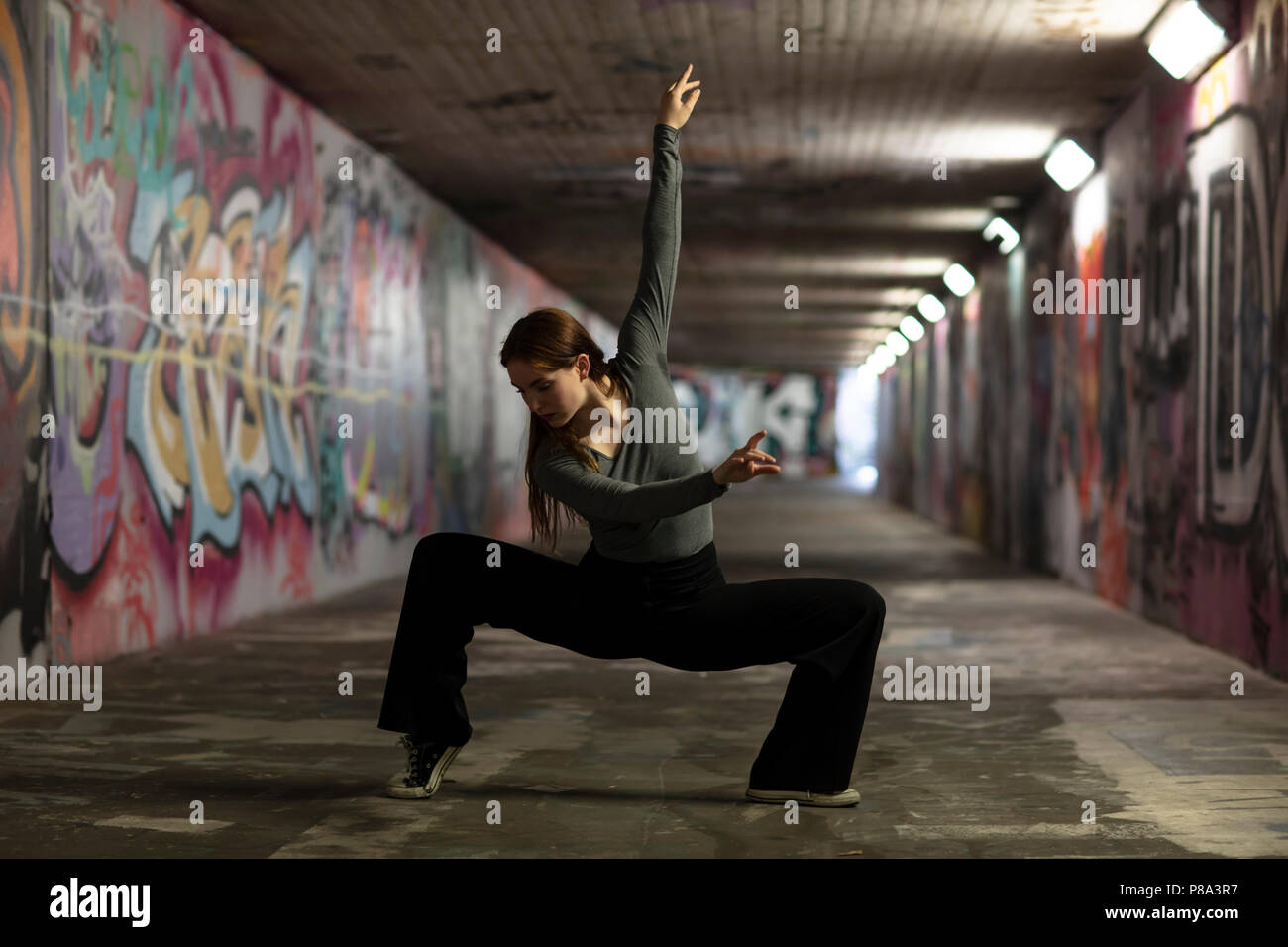 Female modern dancer in motion performing in an tunnel. Full length ...