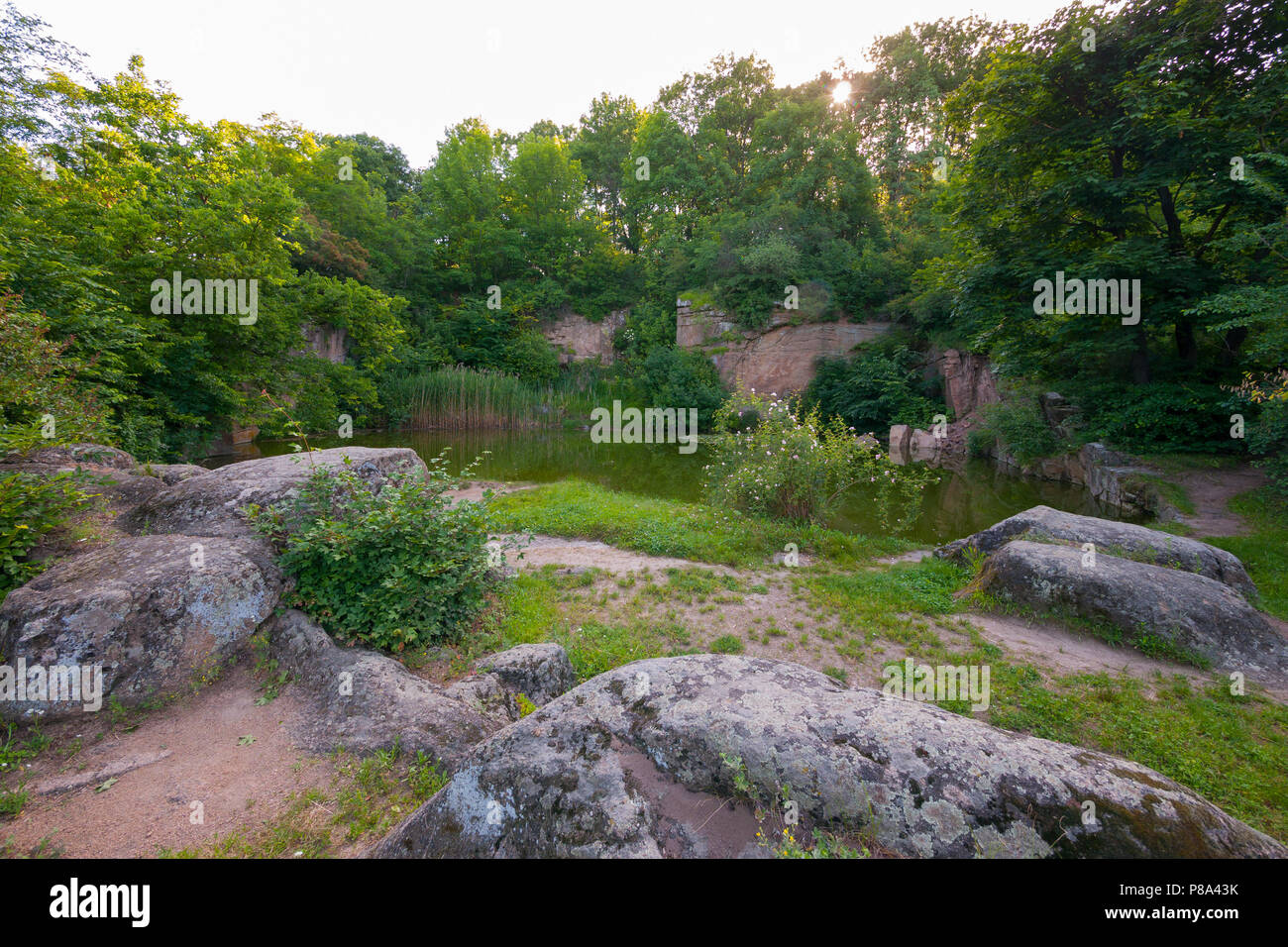 A small green transparent lake on a background near stone boulders and ...