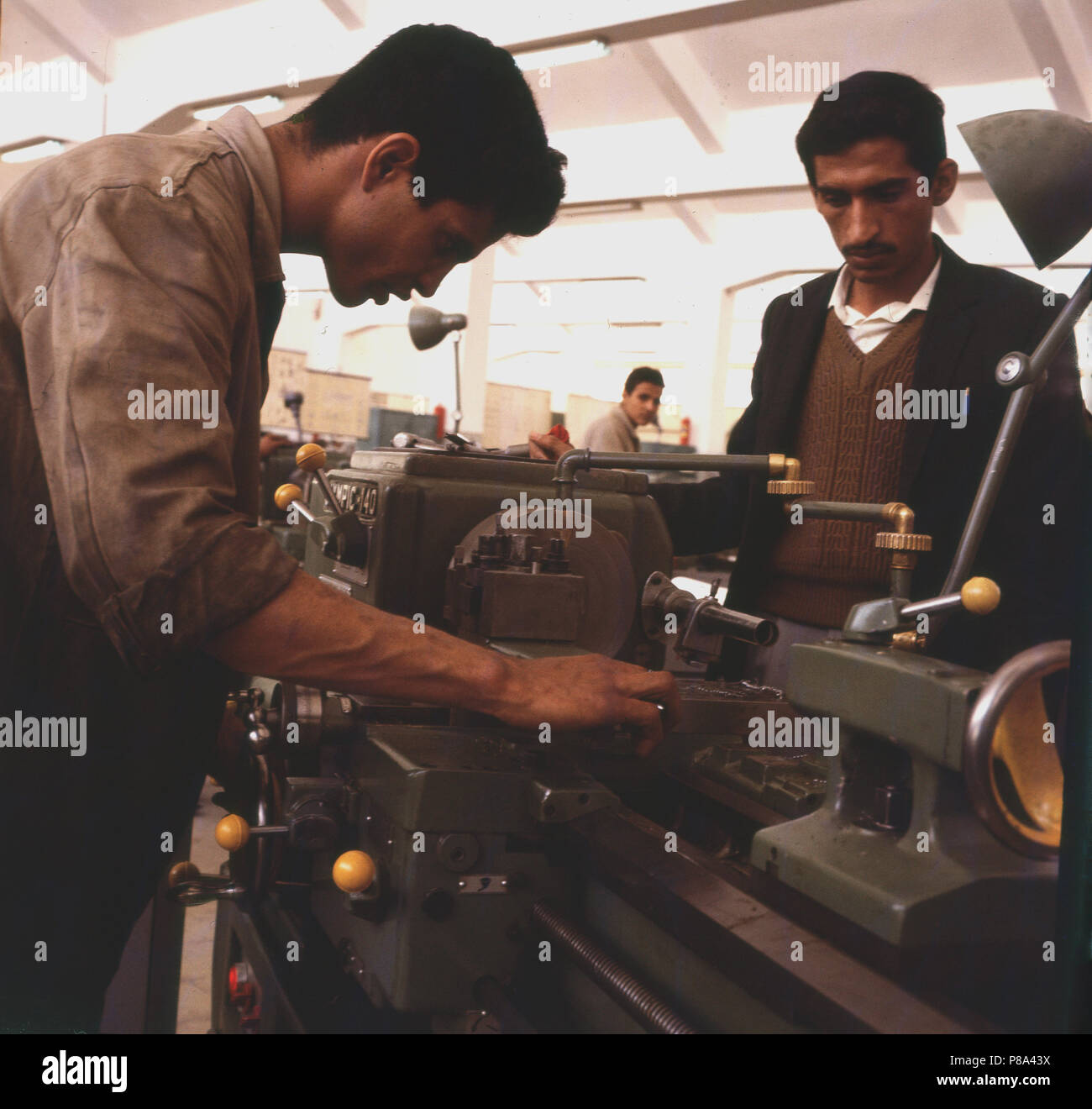 1960s, historical, a young arab male working on an industrial lathe ...