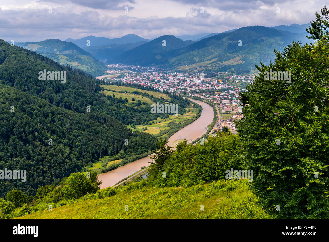 River channel dividing a small rural village and a large green mountain ...
