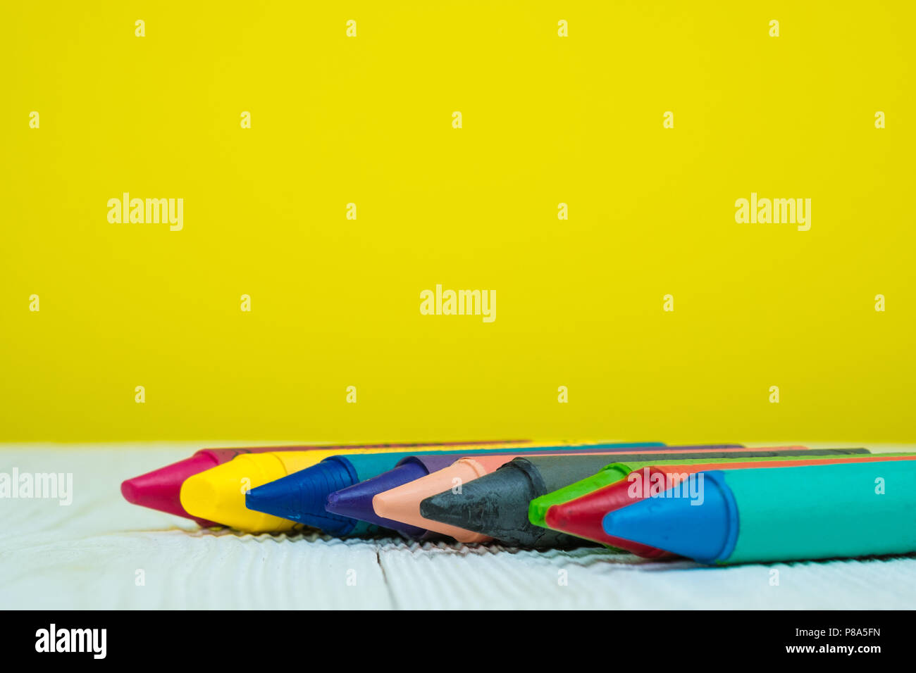 Colourful wax crayons pencils on white wood table with copy space for ...