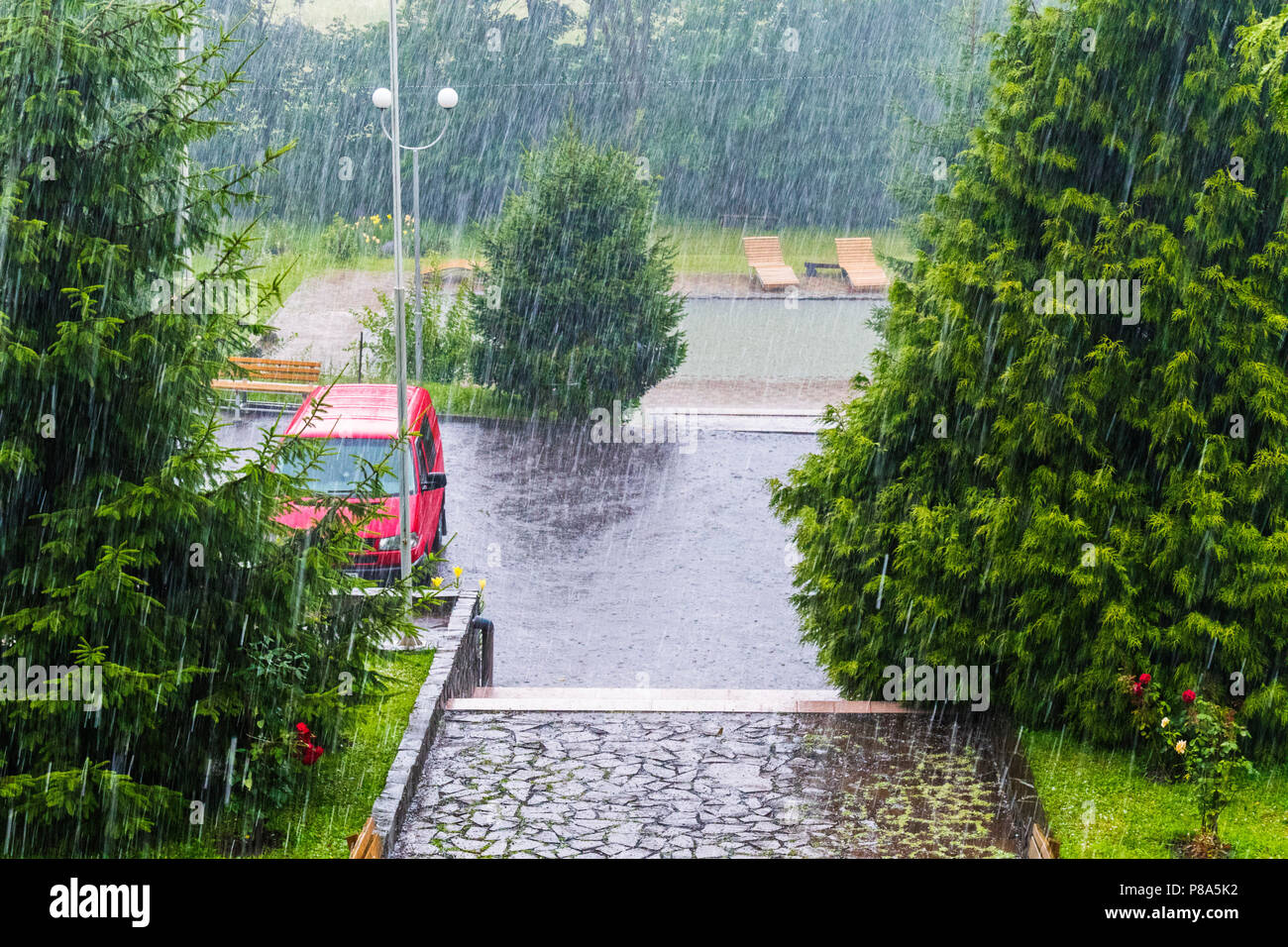 Drops of very heavy rainfall fall on asphalt and trees near the hotel ...