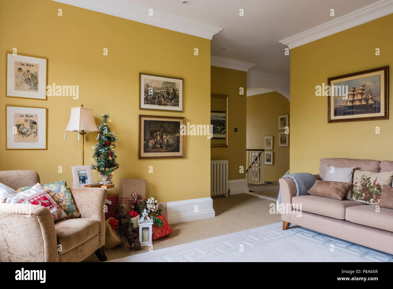 Armchair and sofa with framed artwork in yellow Regency living room ...