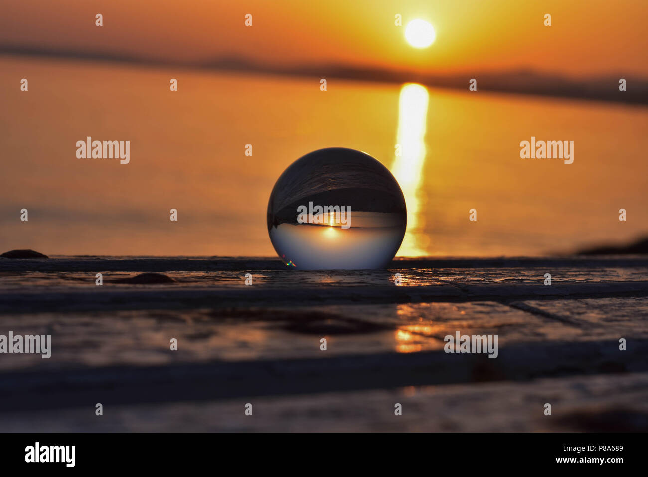 Summer sunset displayed through a transparent glass ball on the beach ...