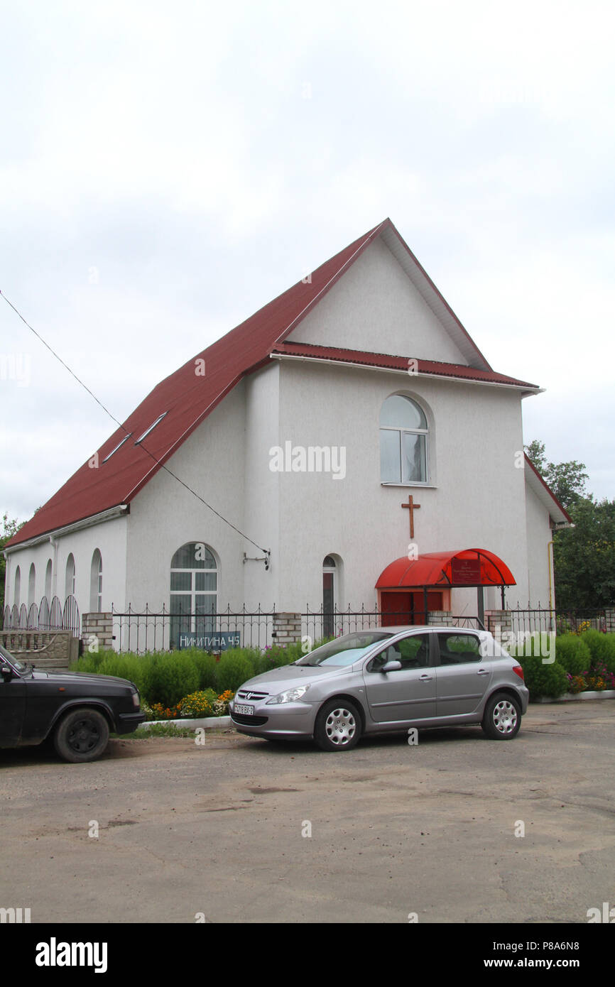 A white prayer house with burgundy tiles and a porch under a red canopy ...