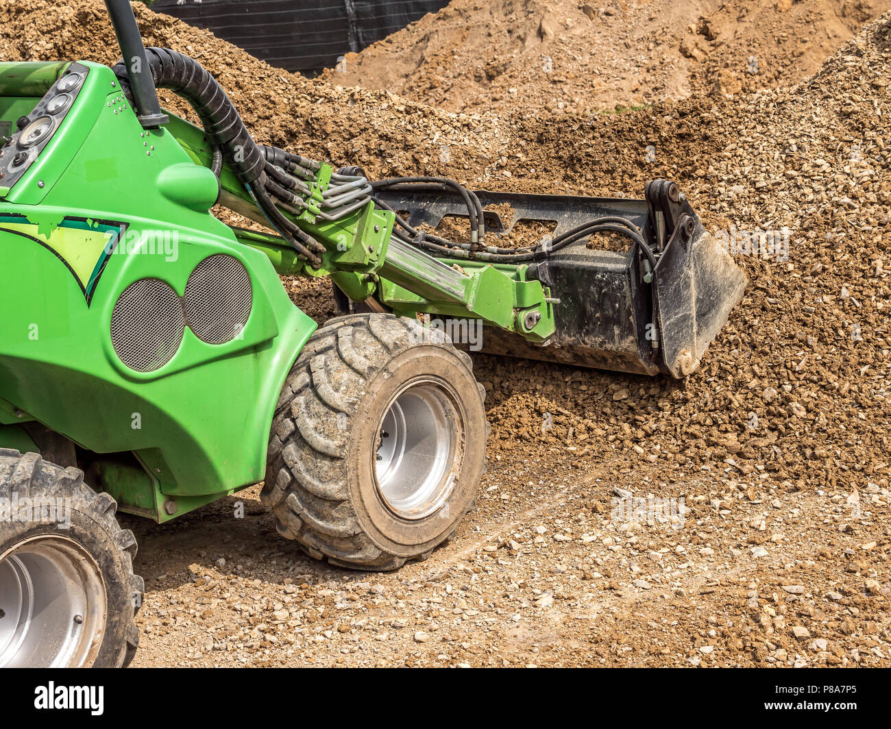 Green skid loader loading gravel Stock Photo - Alamy