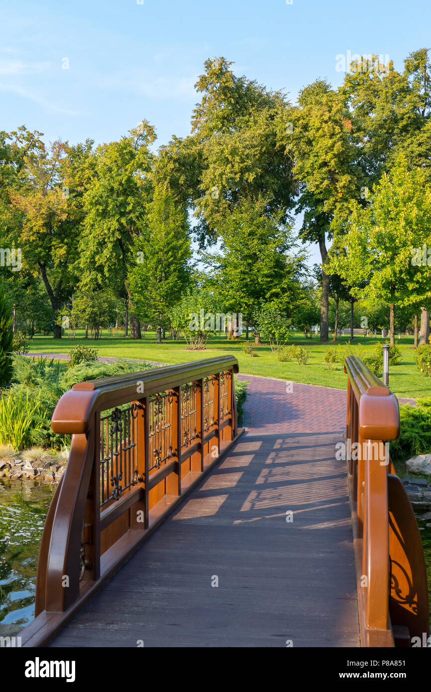 neat pedestrian bridge in the park with lacquered wooden railings . For ...