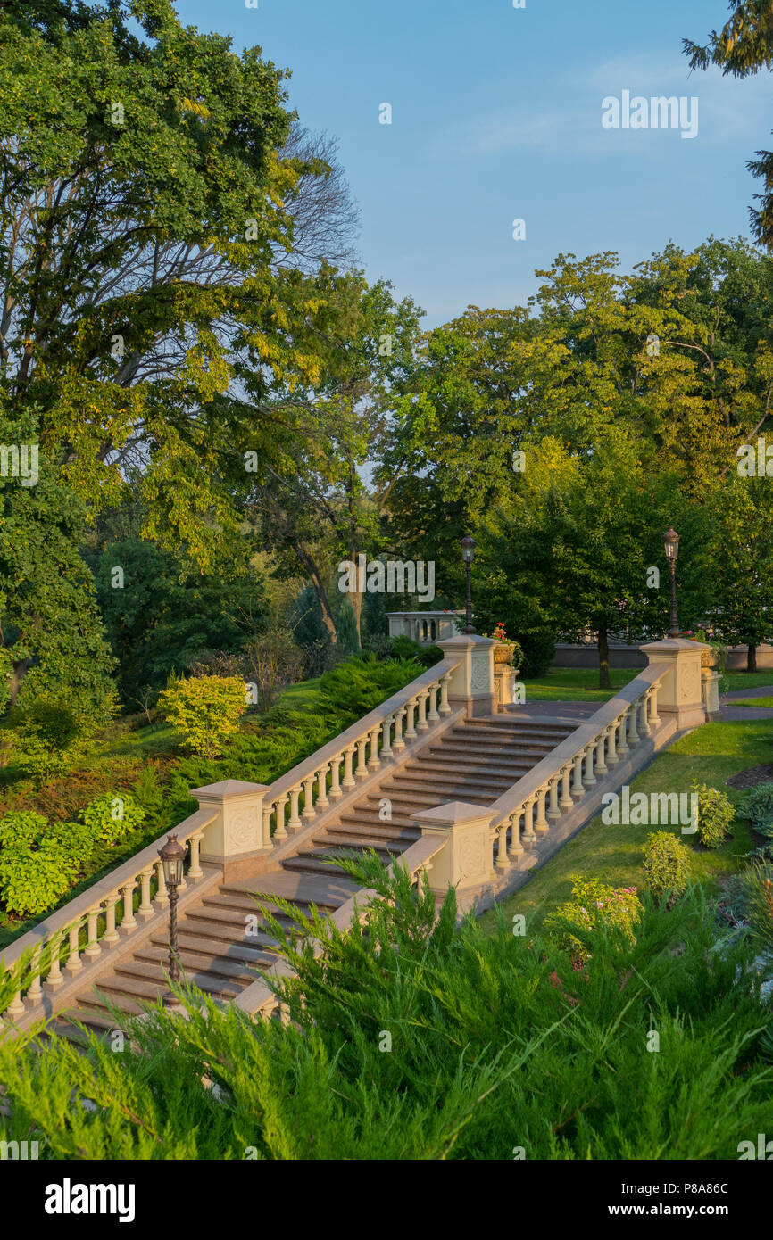 concrete stairs up in a green park with railing and lanterns on the ...