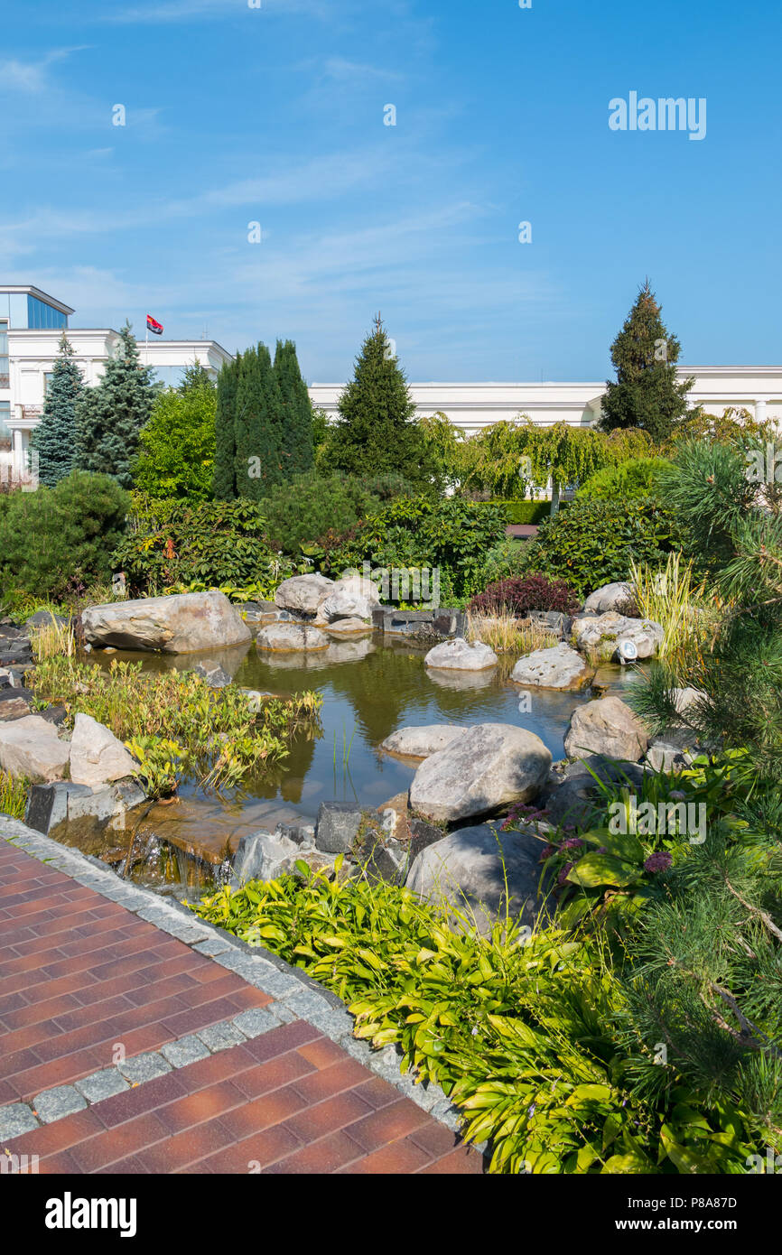 Large decorative stones in a small pond in a park among green bushes ...