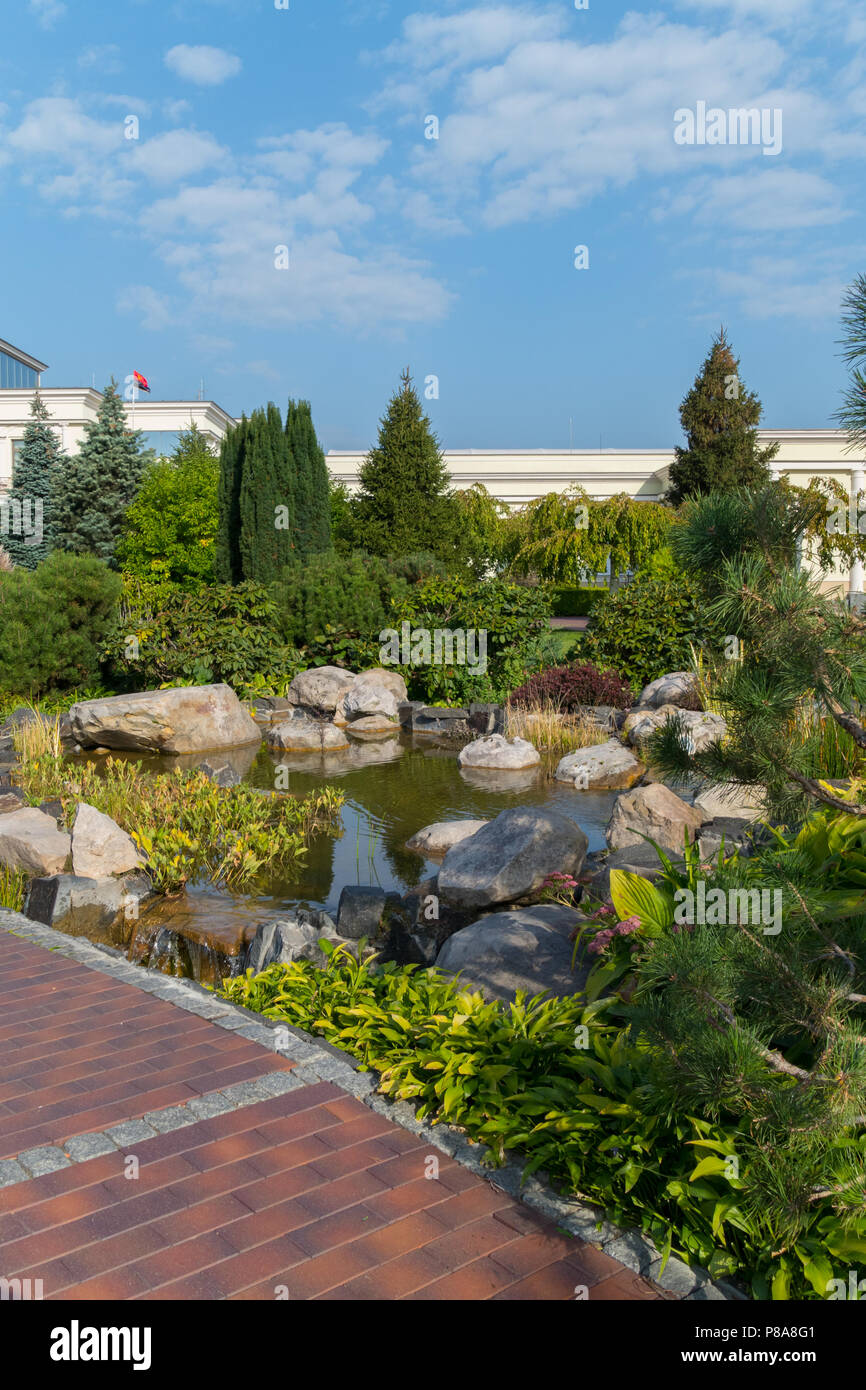 A small pond with stones and a walkway near it. Place for walking . For ...