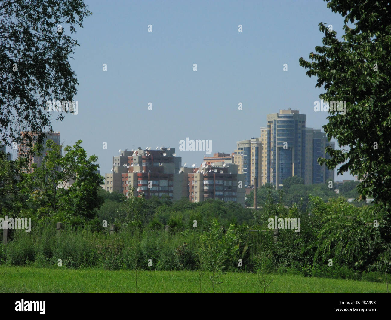 Urban high-rise buildings against a background of green trees and ...