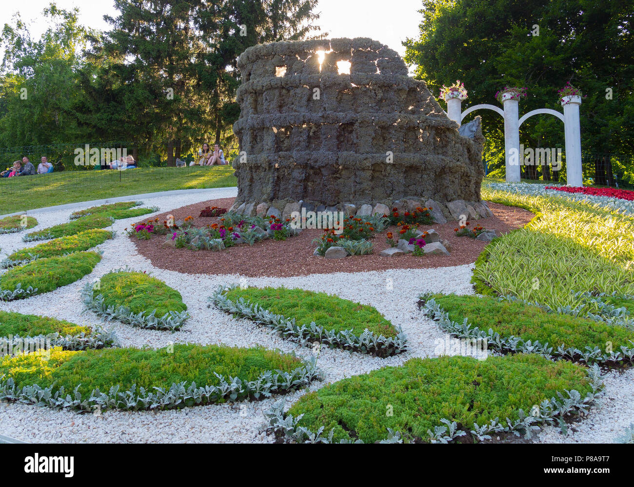 Beautiful flowerbed and sculpture of a partially destroyed Colosseum on ...