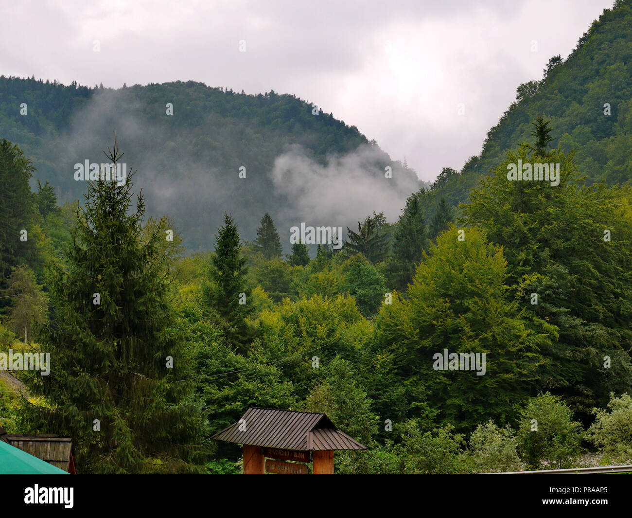 Mountain peaks in the haze of mist and the roof of the well at their ...