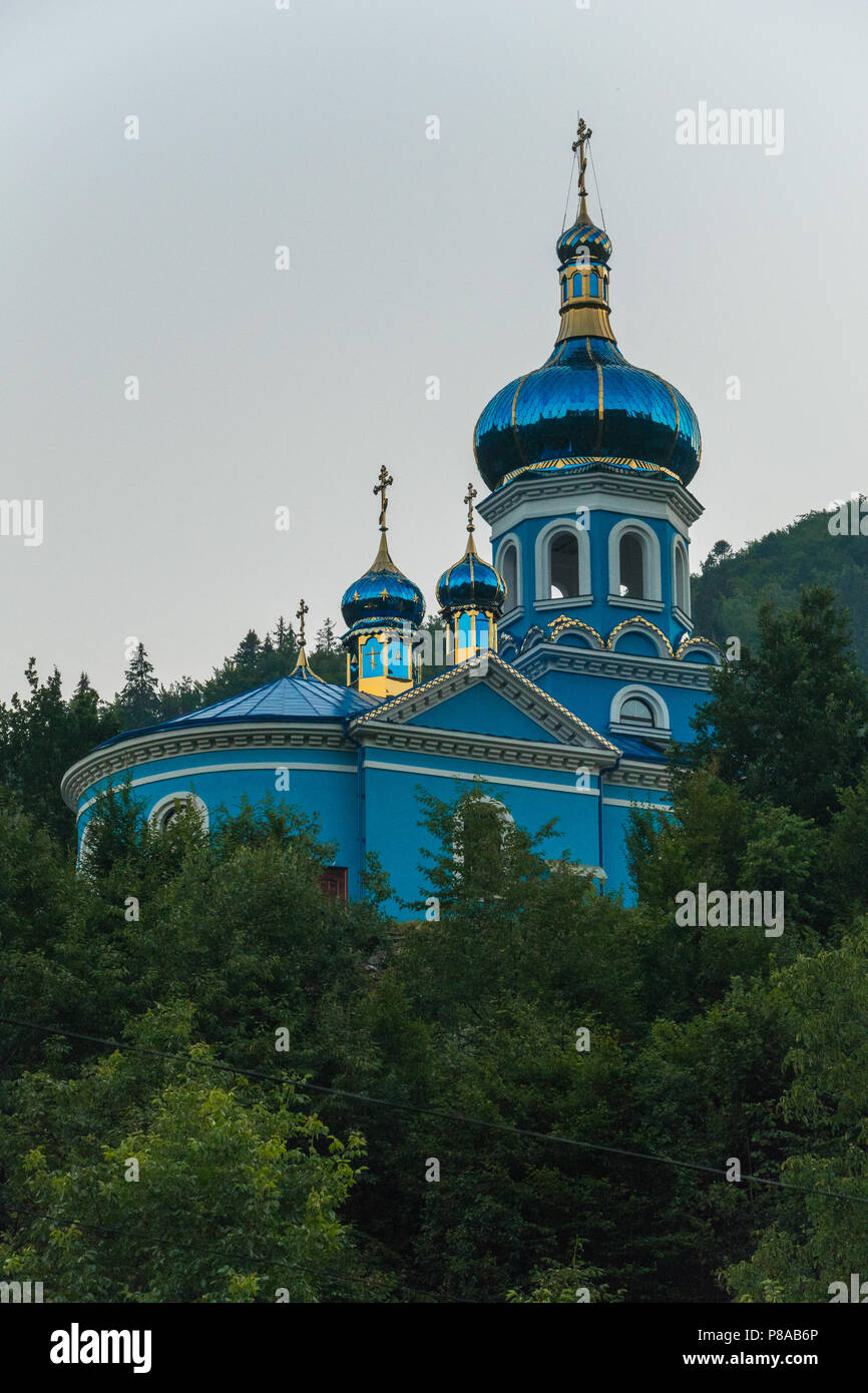 blue orthodox church among green tall trees under a blue cloudless sky ...