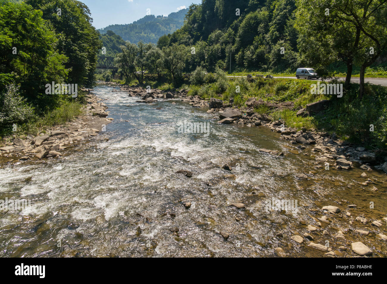the road along the gradually running mountain river and the car driving ...