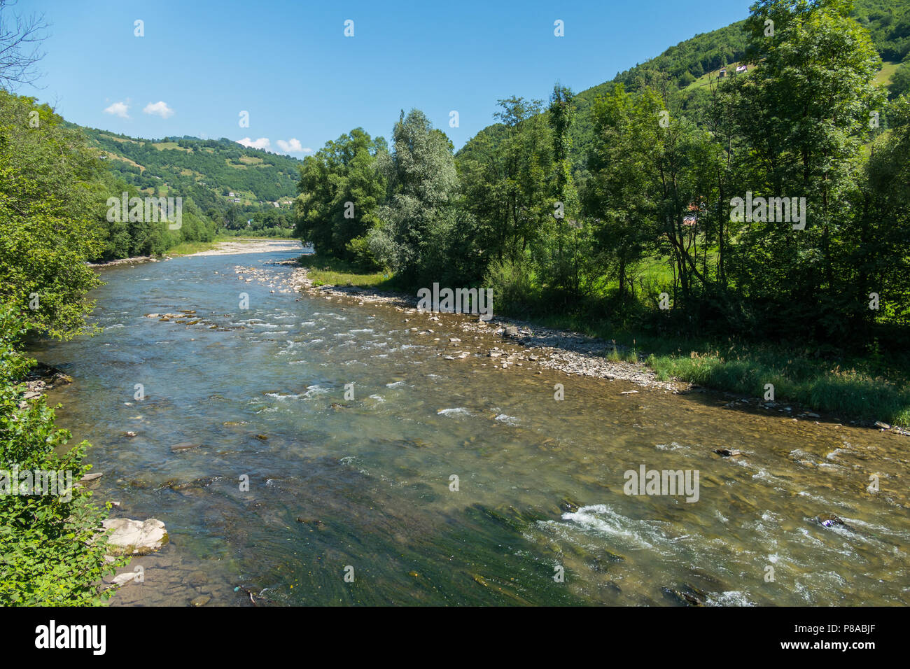 a deep blue sky with clouds and the mountains below and the current ...