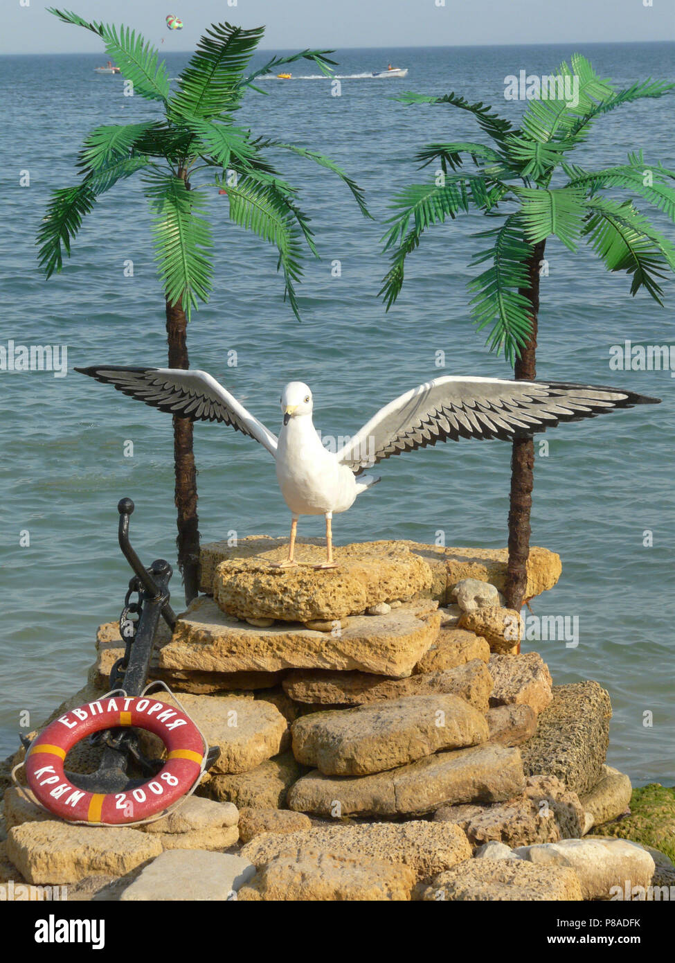 a statue of a white gull with palm trees on the background of a blue ...