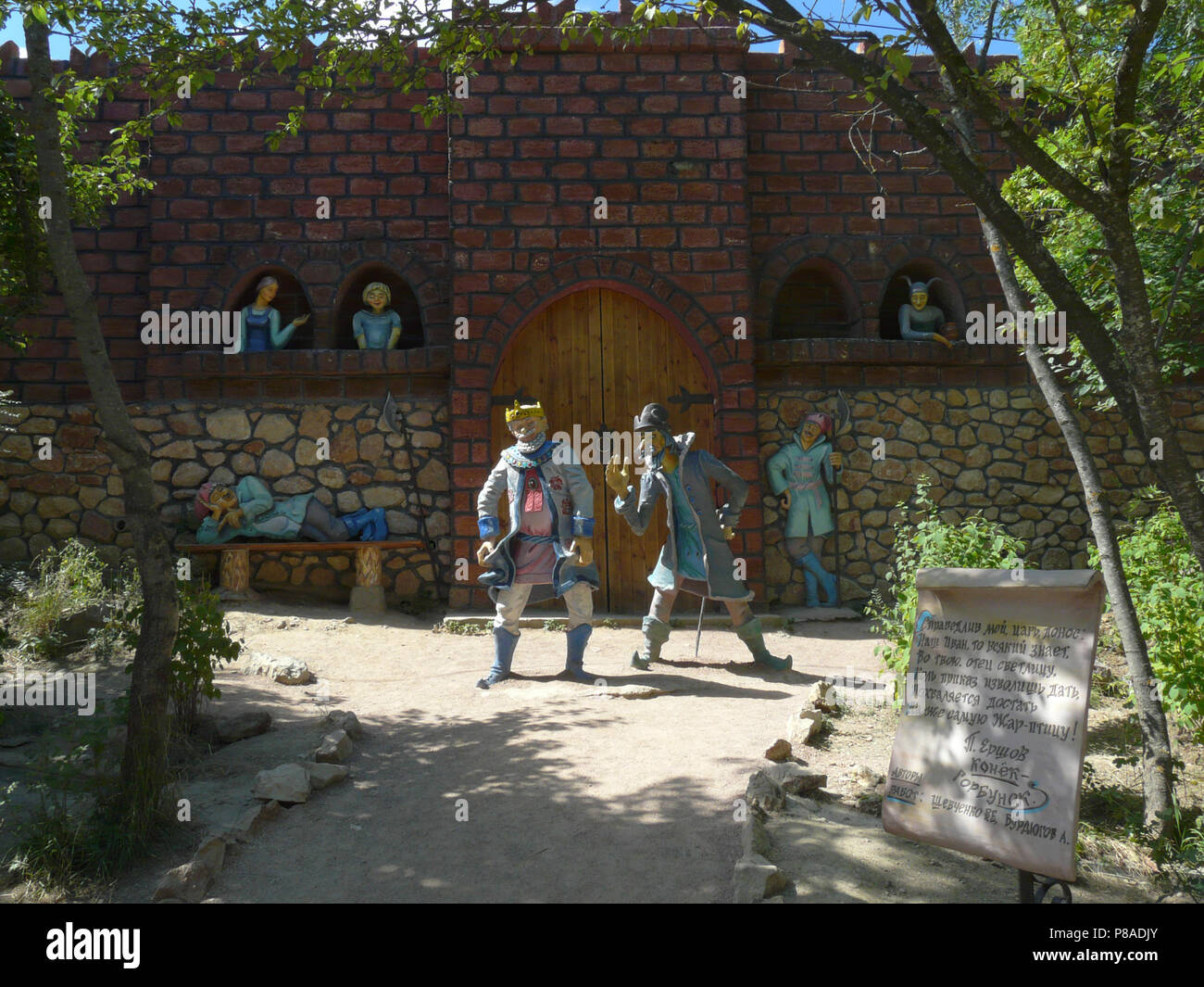 brick wall of the castle with a gate and statues in the park for ...