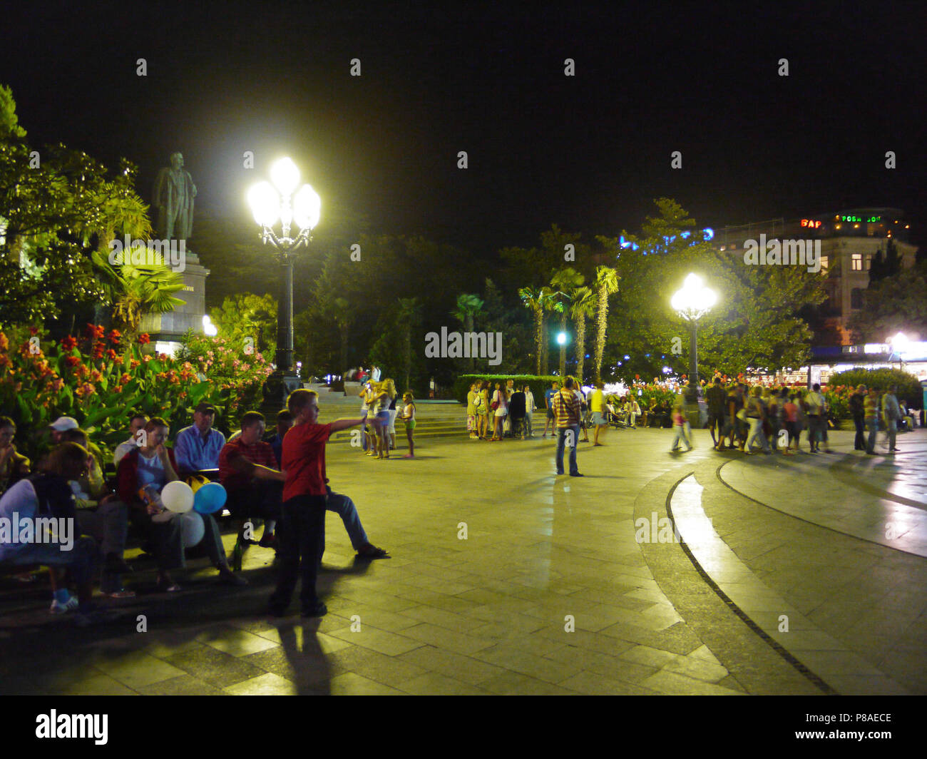 a crowded city square with monuments in the park with tall green trees ...