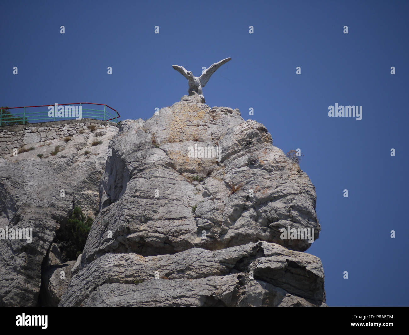 Sculpture of a bird made of stone with spaced wings standing on a low ...