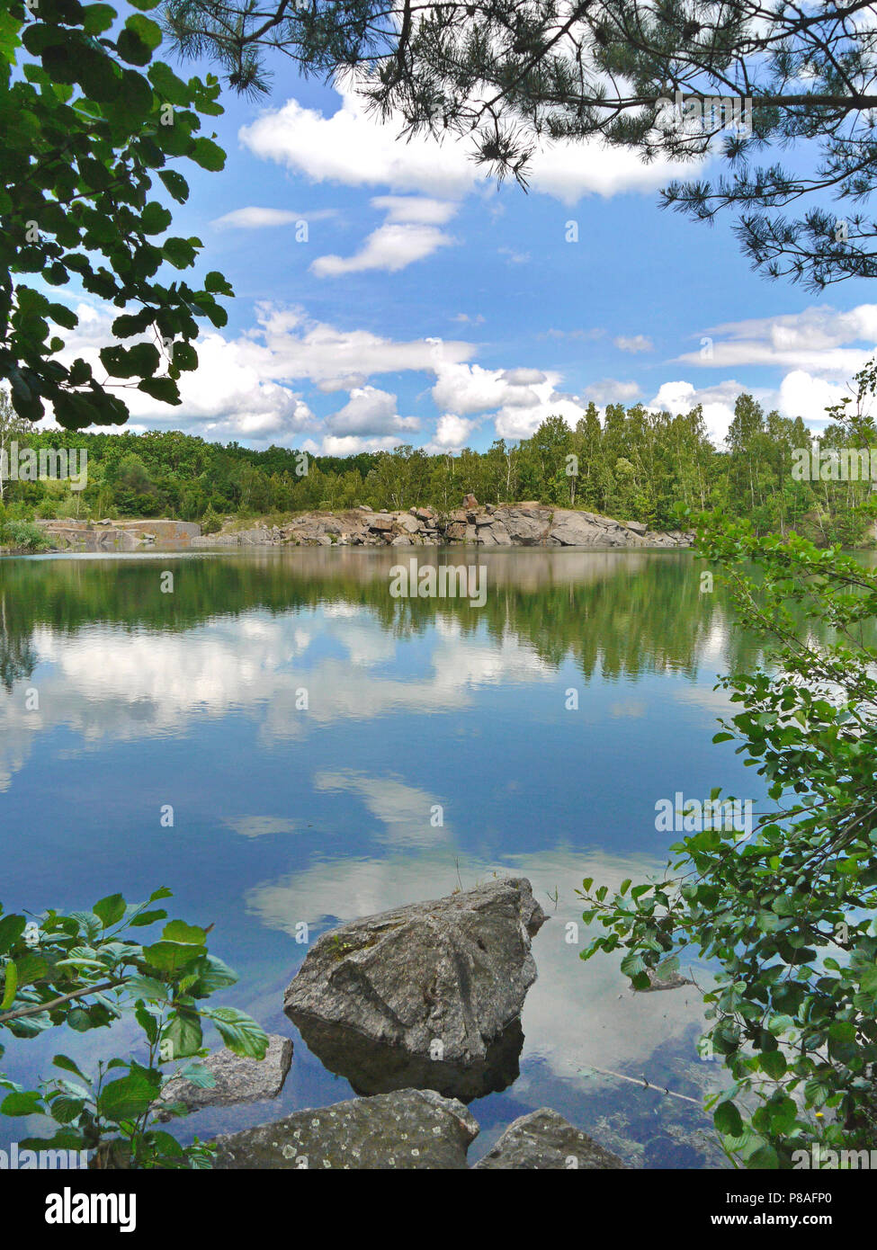 a deep blue sky with slowly floating clouds and a sleepy little pond at ...