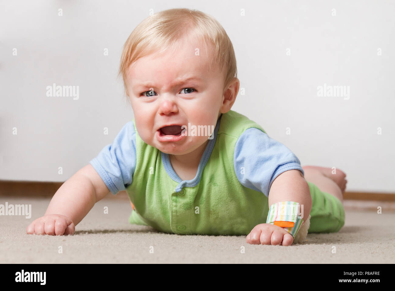 A young baby having a fit on the ground crying and making a pout face ...