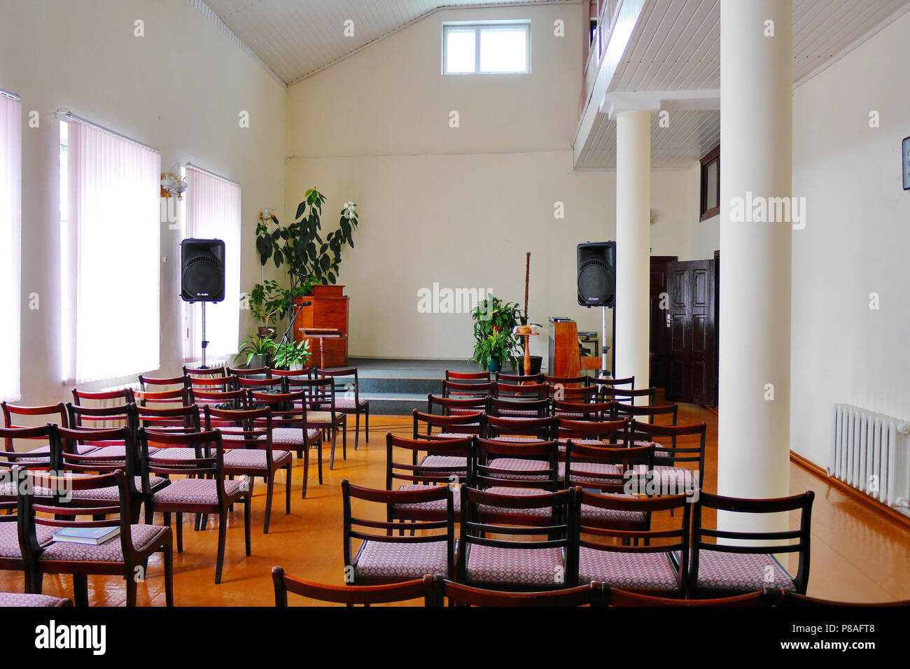 A cozy hall in a room with high ceilings and white walls with rows of ...