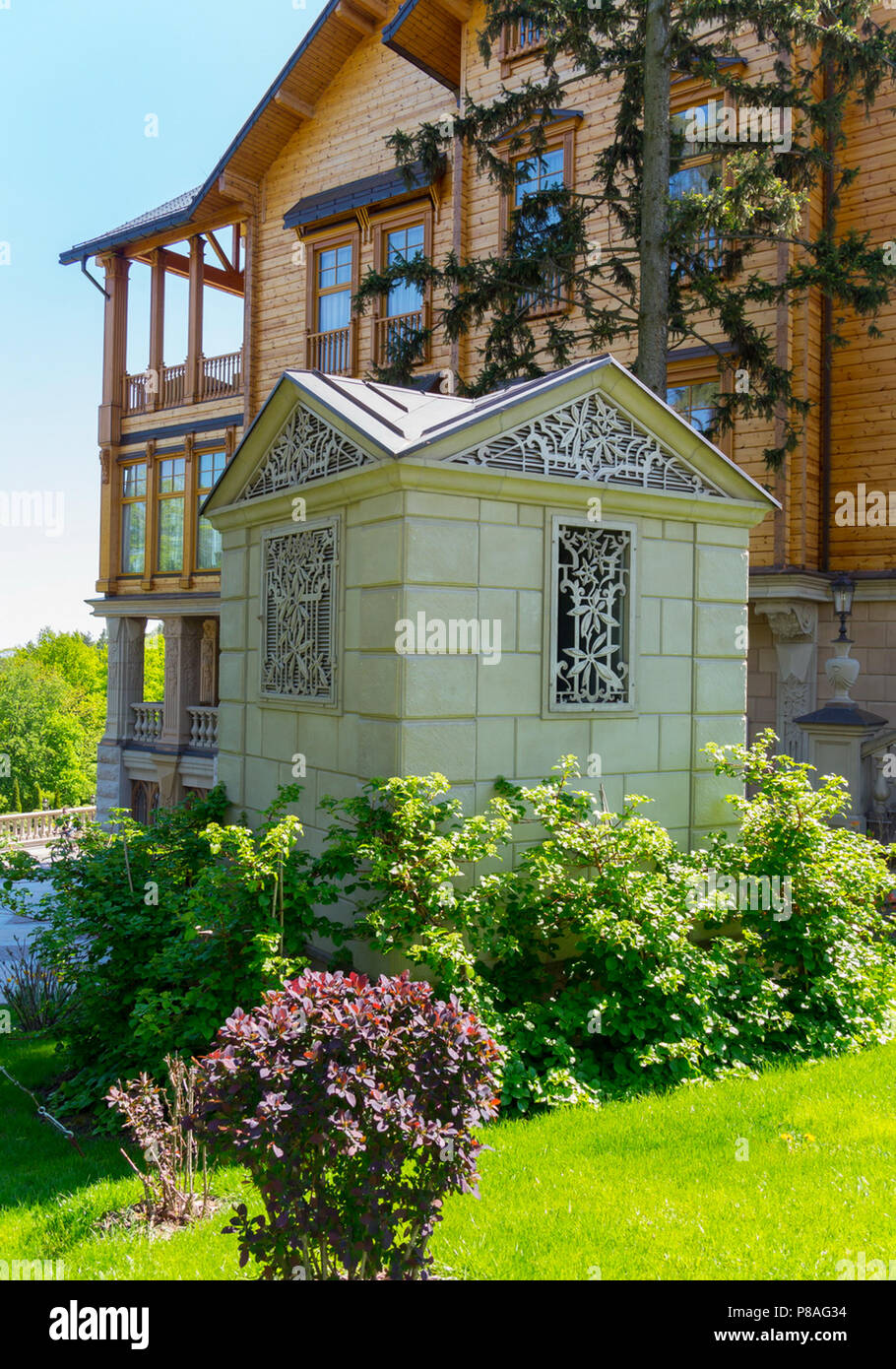a small decorative building of white stone in front of a huge wooden ...