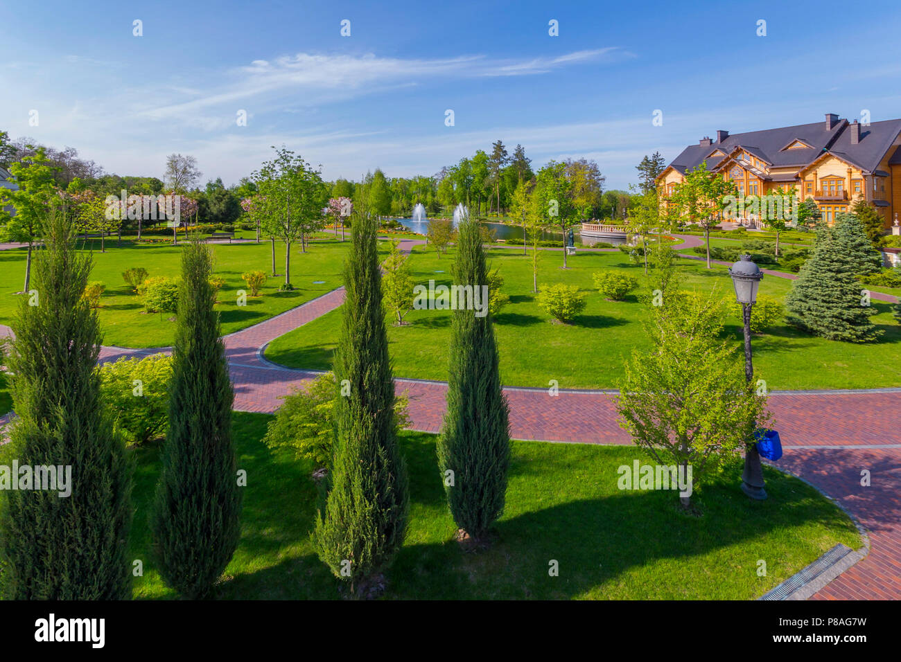 a huge lawn in front of a wooden mansion with stone paths, a green lawn ...