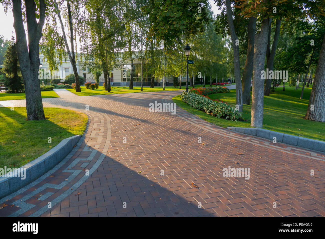 A wide park walkway with decorative green trees near the modern ...