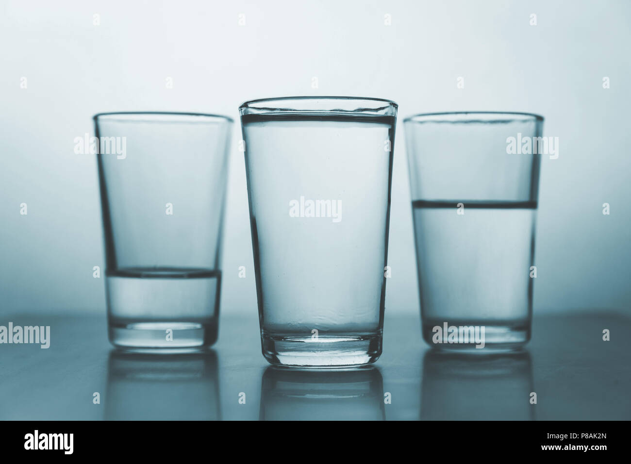 studio shot of three water glasses each one have more water than the ...