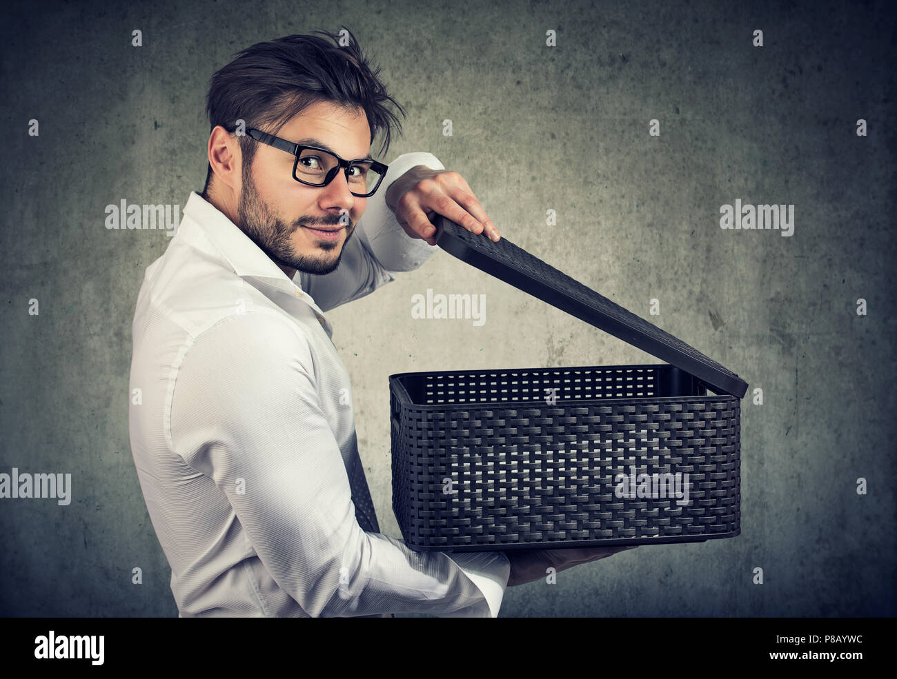 Sly crafty man holding and opening a box and looking with smirk at ...