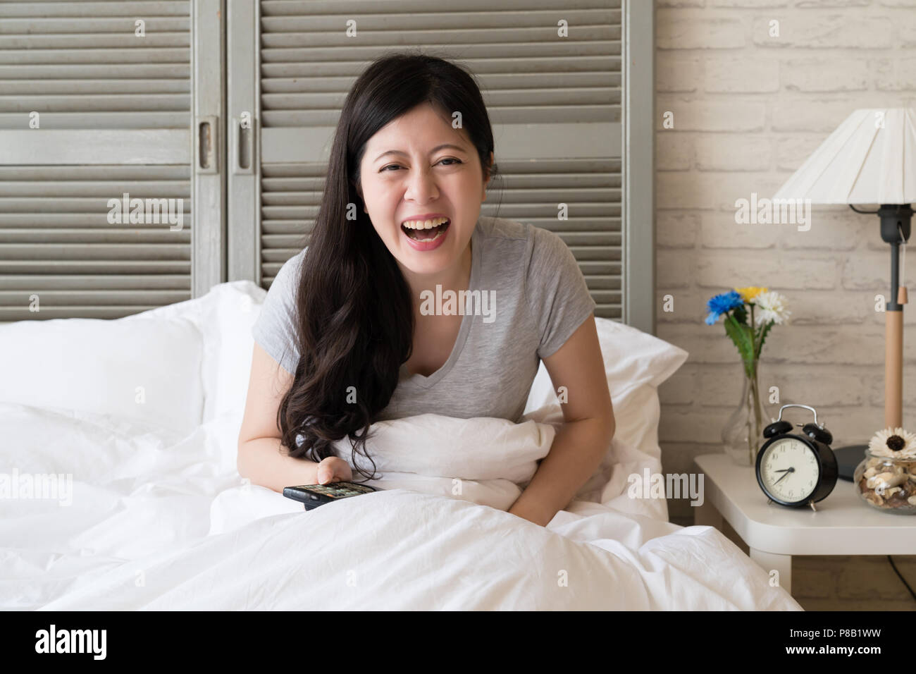 woman sitting in the bed and watching the TV agitated and can't help ...