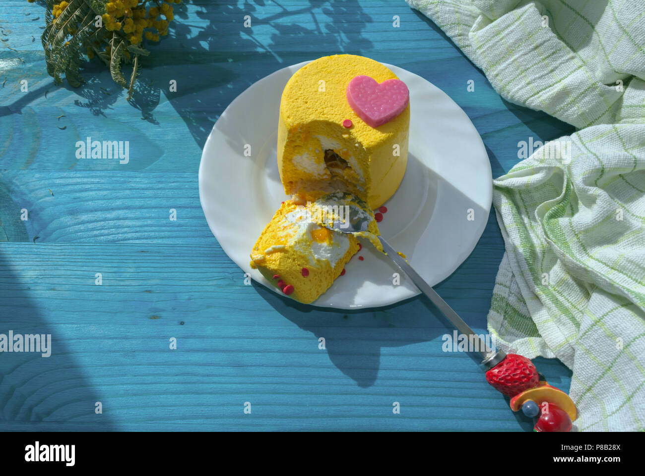 bitten off piece of yellow minin cake on white plate with blue wooden ...