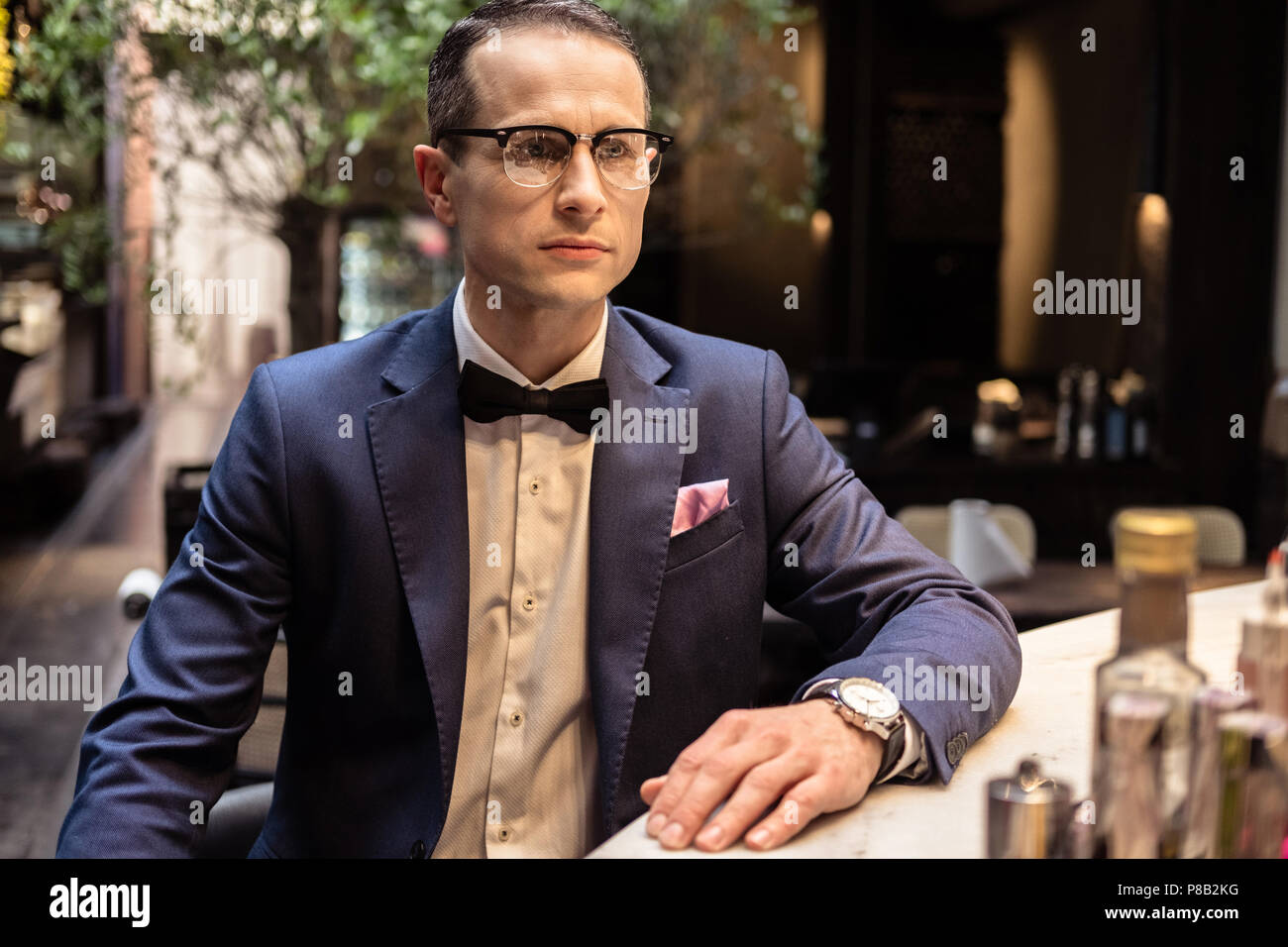 handsome man in stylish suit sitting at bar counter of luxury ...