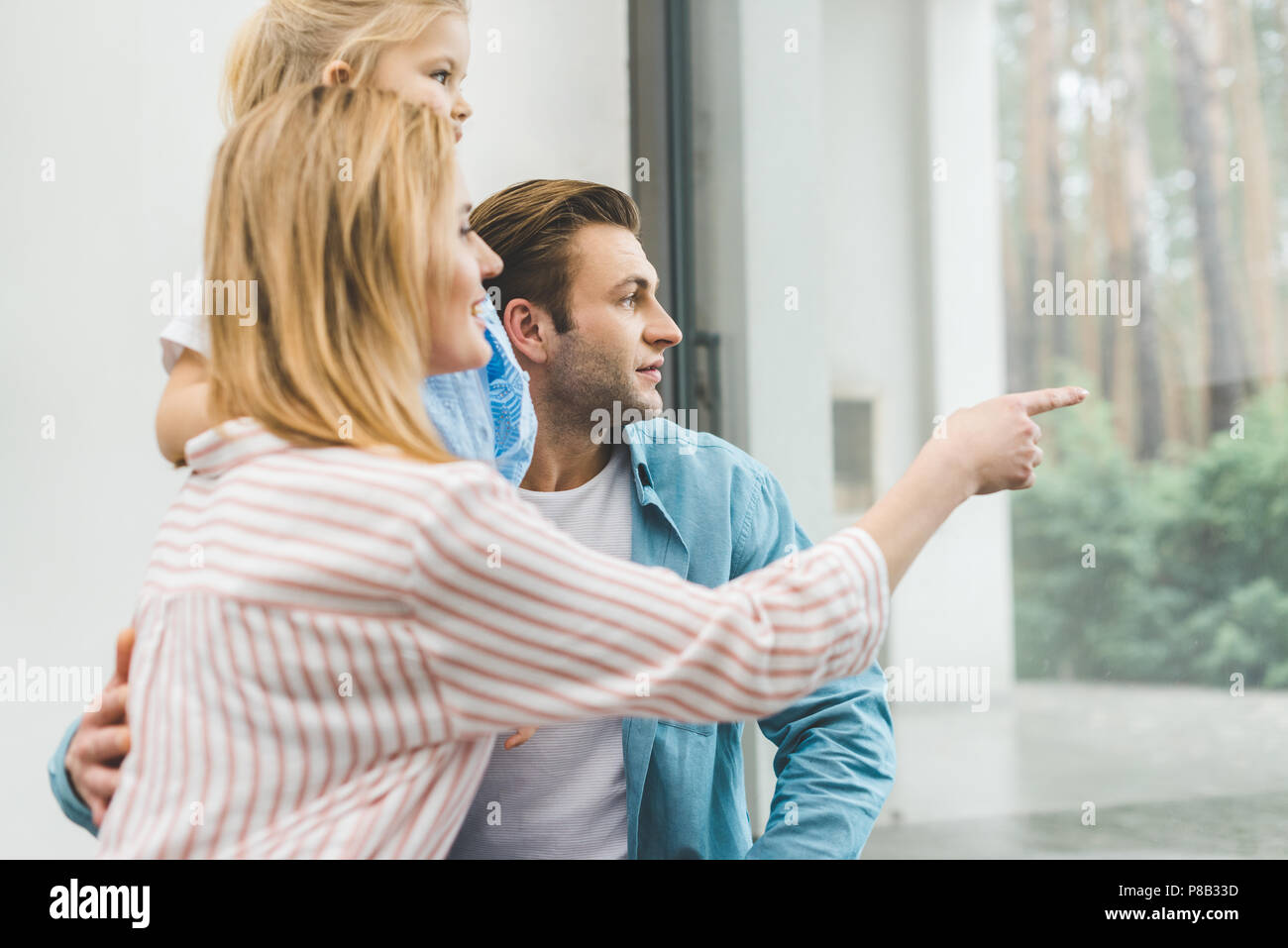 side view of family looking out window together at home Stock Photo - Alamy