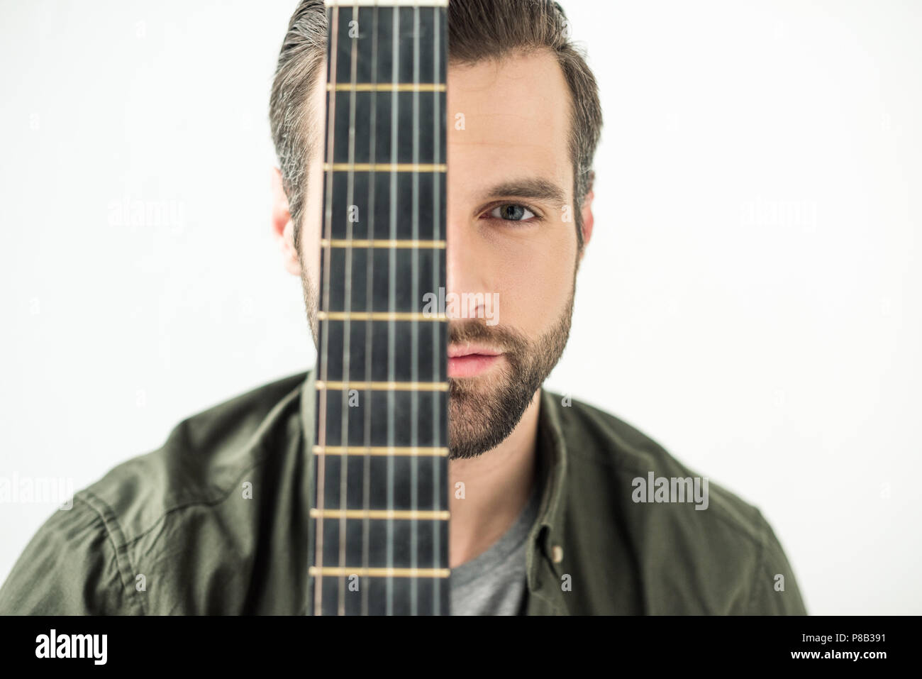handsome man covering eye with acoustic guitar neck isolated on white ...