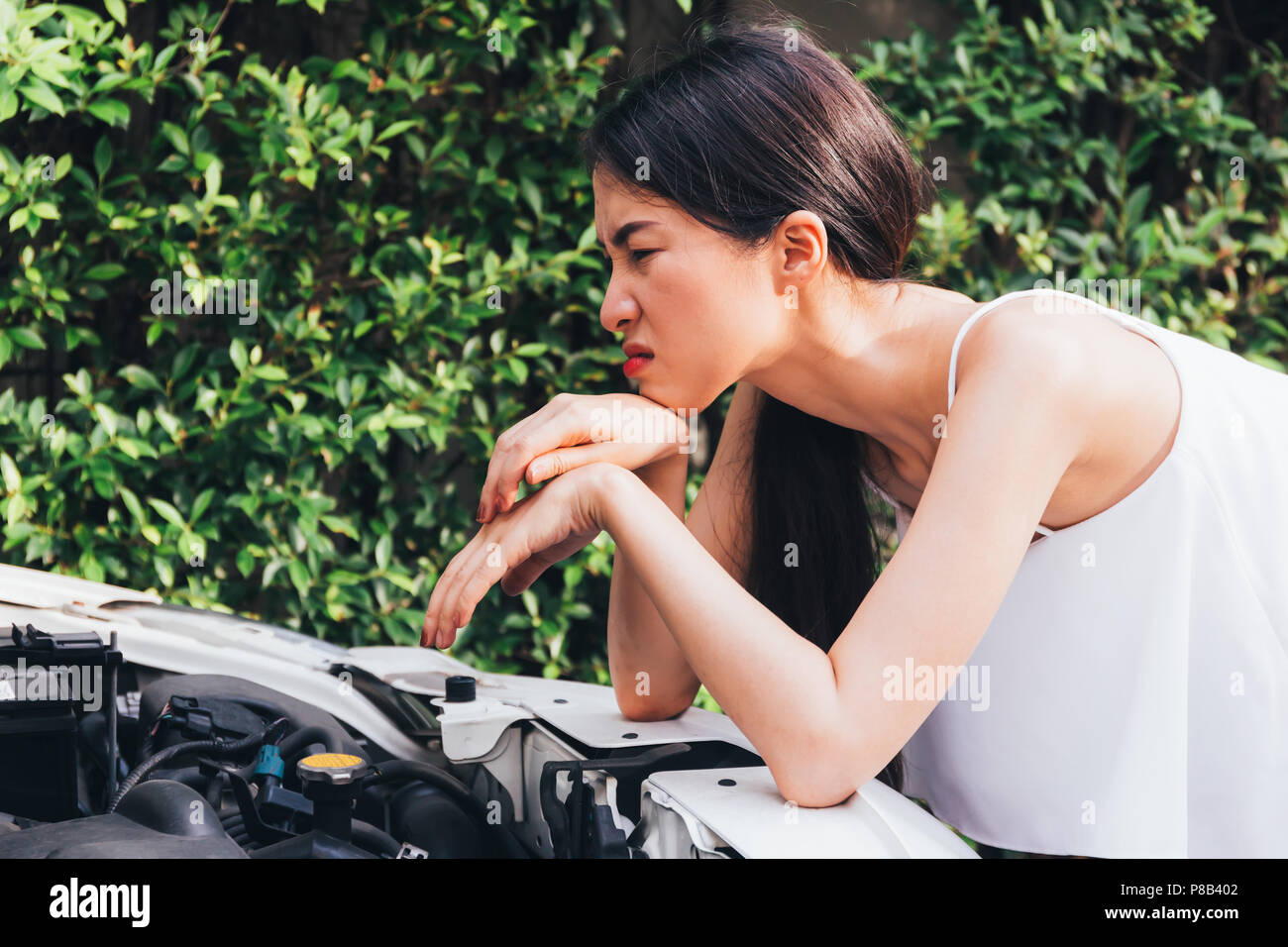 Asian woman frustrated and angry checking her broken car and failed ...
