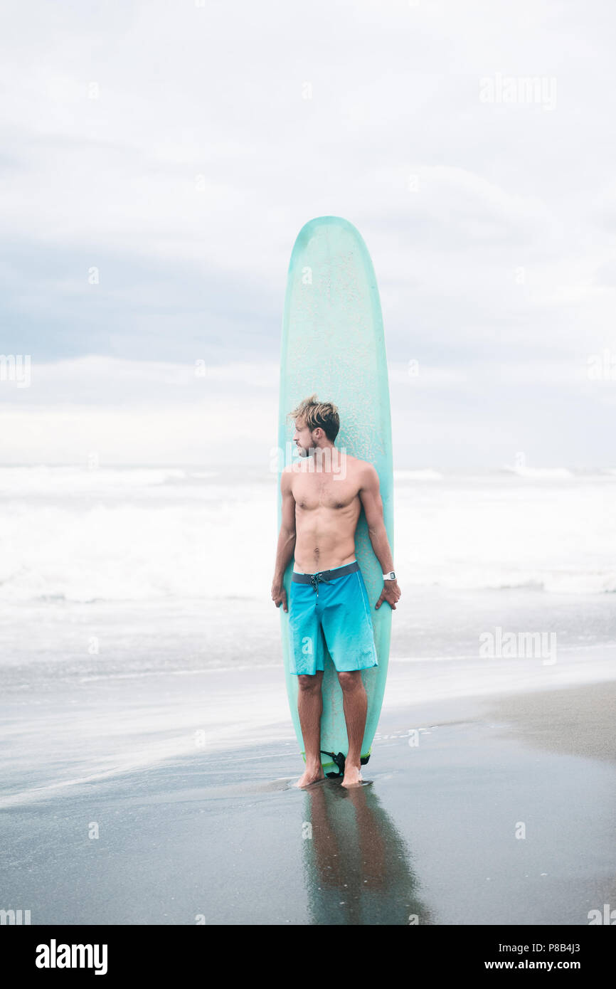 shirtless surfer standing with surfboard in Bali, Indonesia Stock Photo ...