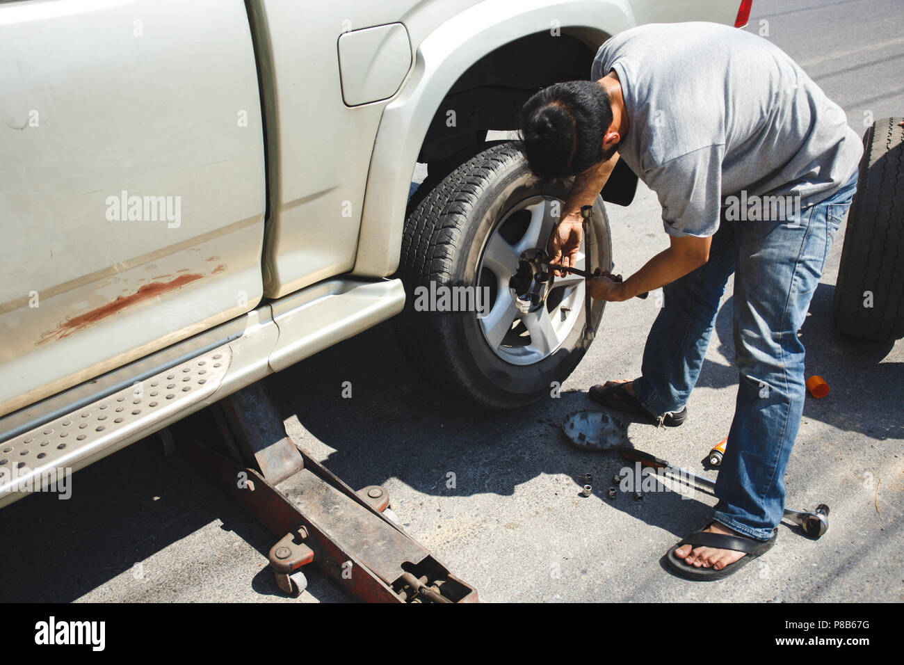 A man changing the wheel at the side of the road Stock Photo - Alamy
