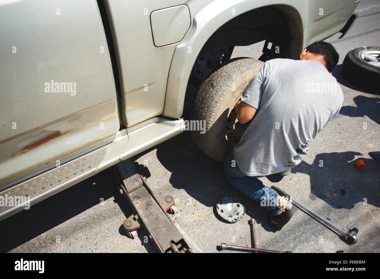 A man changing the wheel at the side of the road Stock Photo - Alamy