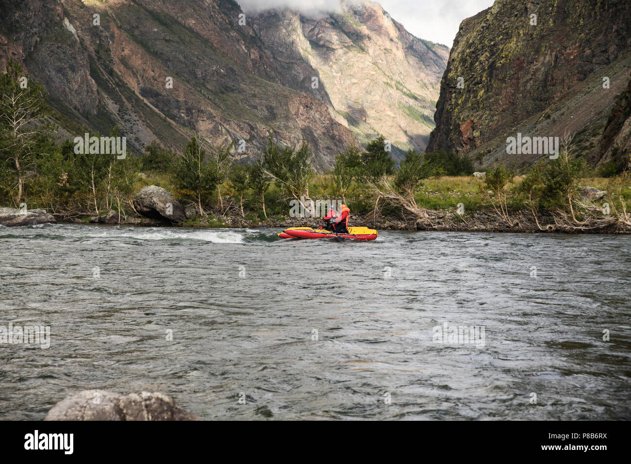 side view of people on kayaks rafting on mountain river and beautiful ...