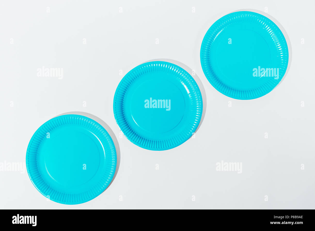 Three disposable plates of turquoise color on white background, flat ...