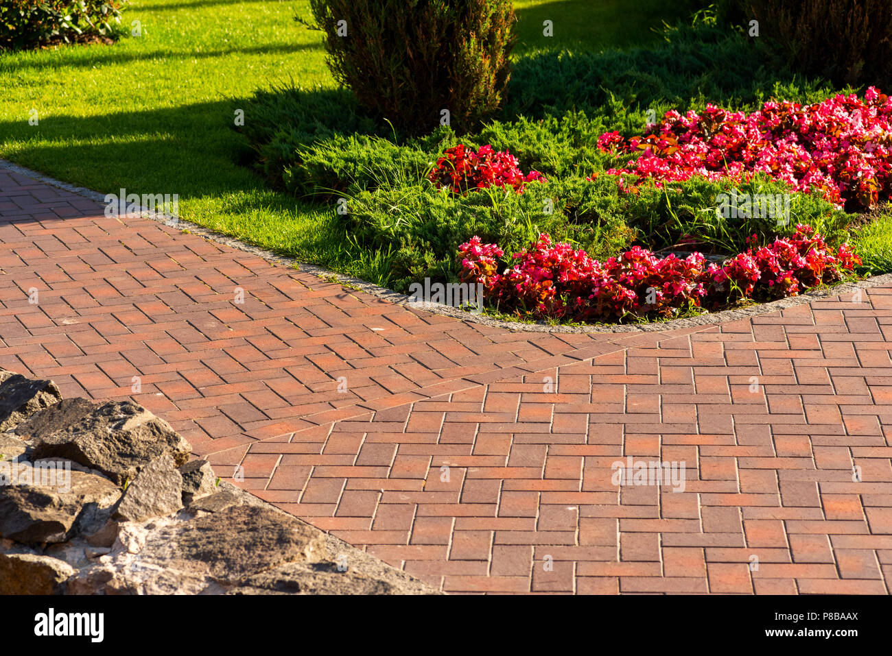 Path from red paving slab next to flowers Stock Photo - Alamy