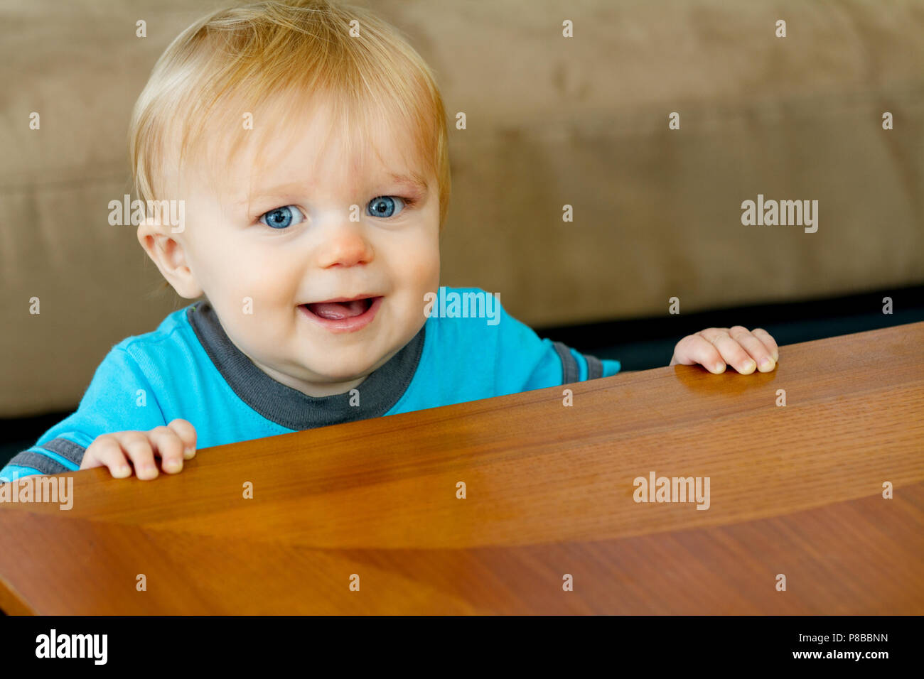 Toddler against the table trying to hold himself up while learning out ...