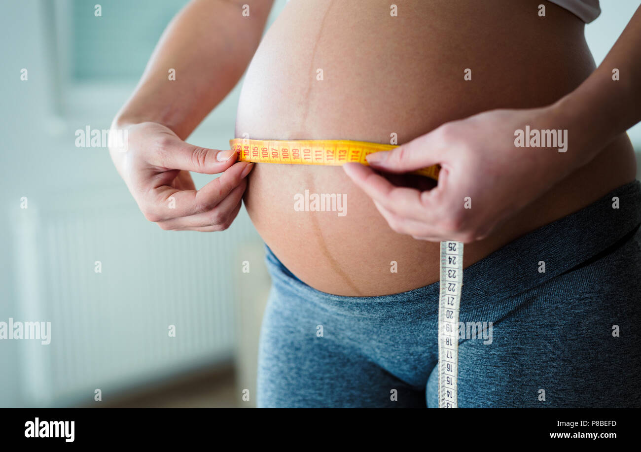 Pregnant woman measuring stomach with measuring tape Stock Photo - Alamy