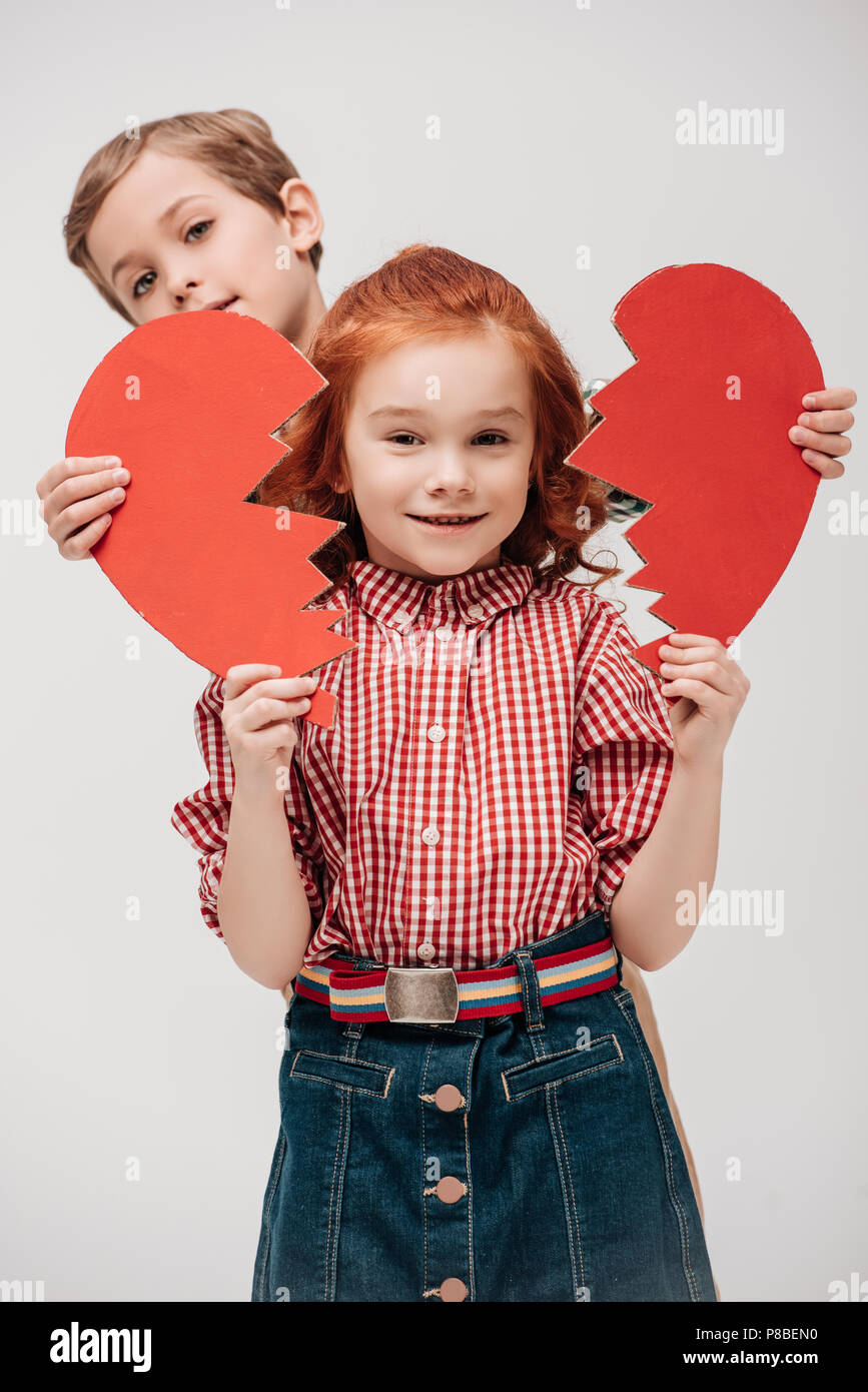 little boy holding parts of broken heart and adorable little girl ...