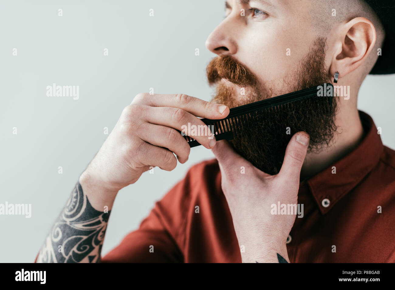 side view of tattooed man combing beard isolated on white Stock Photo ...