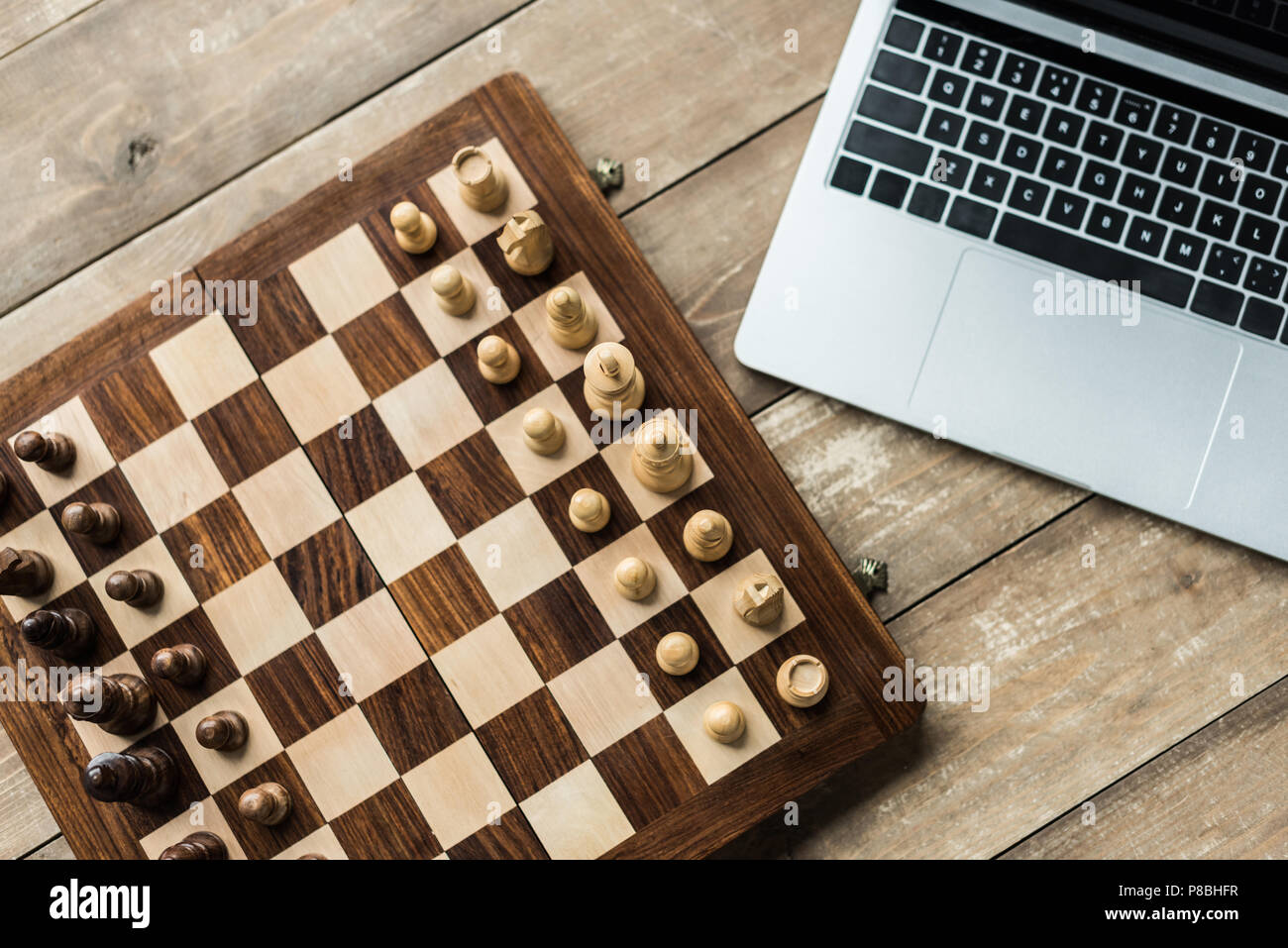 Laptop and chess board with figures on rustic wooden surface Stock ...